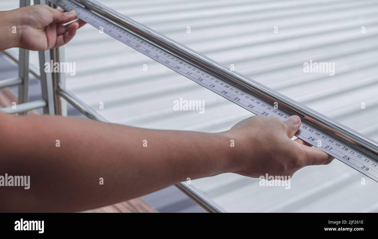Measurement concept. Someone measures a size of balcony railing rod by ...