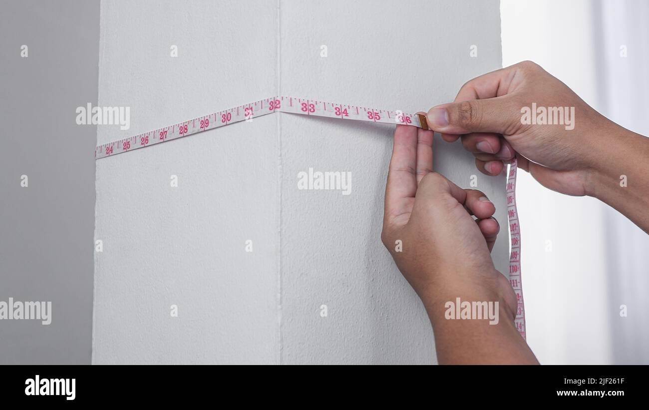 Measurement concept. Someone measures a length of house pillar by waist ...