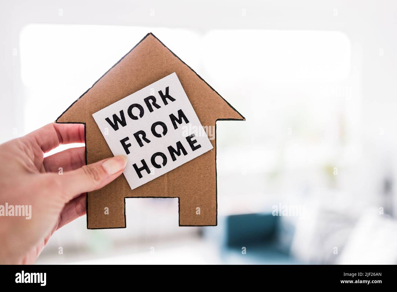work from home sign being hold in front of out of focus living room ...