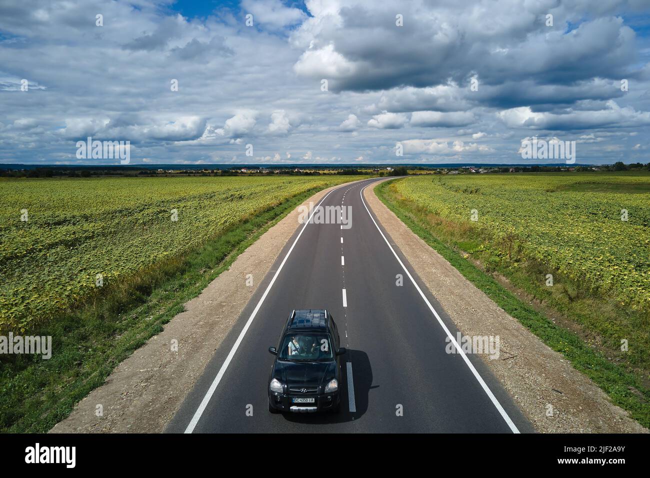 Aerial view of intercity road between green agricultural fields with ...