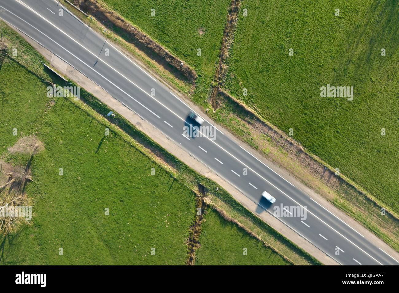 Aerial view of intercity road between green agricultural fields with ...