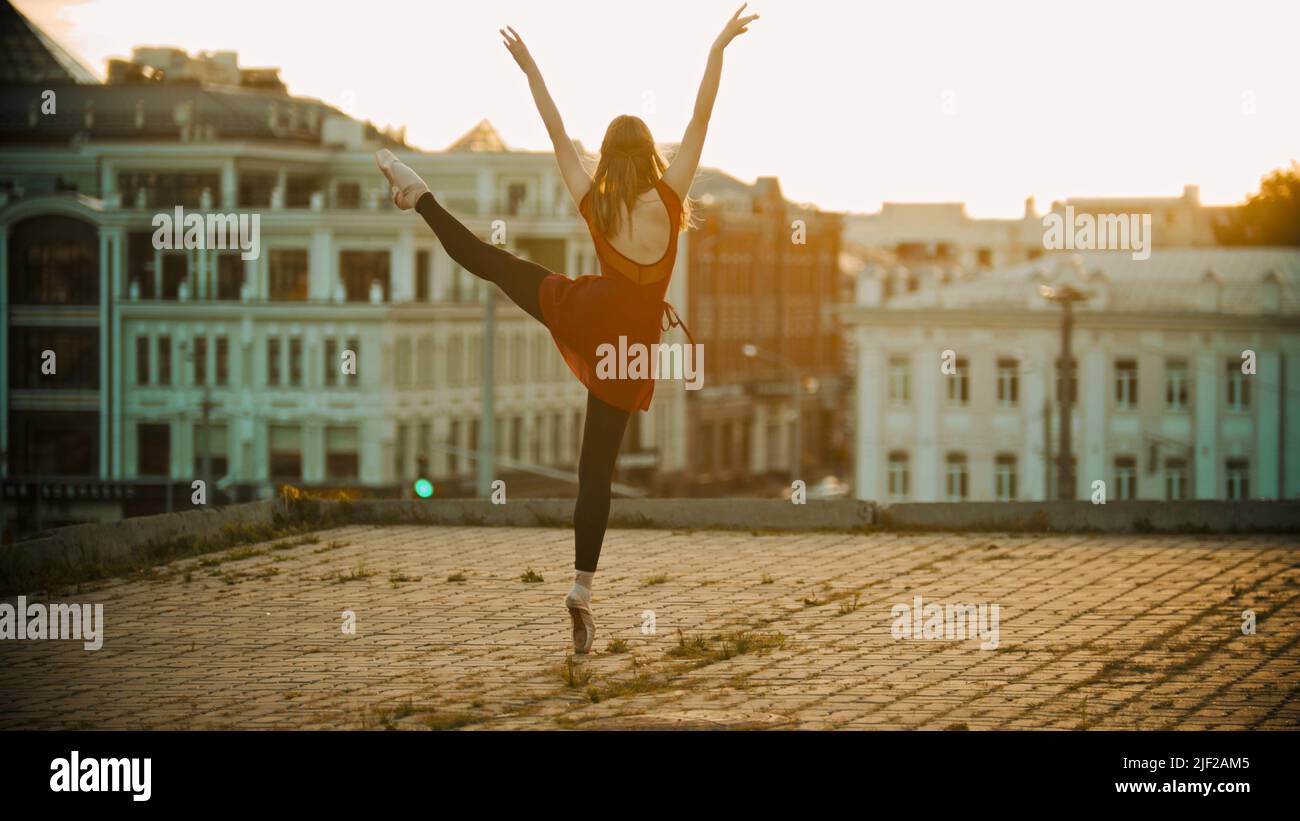 Young woman in red dress standing in the graceful balet pose on the ...