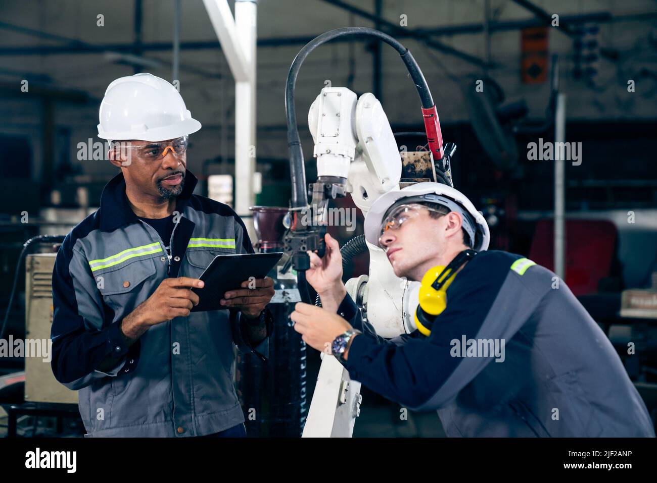 Factory workers working with adept robotic arm in a workshop . Industry ...