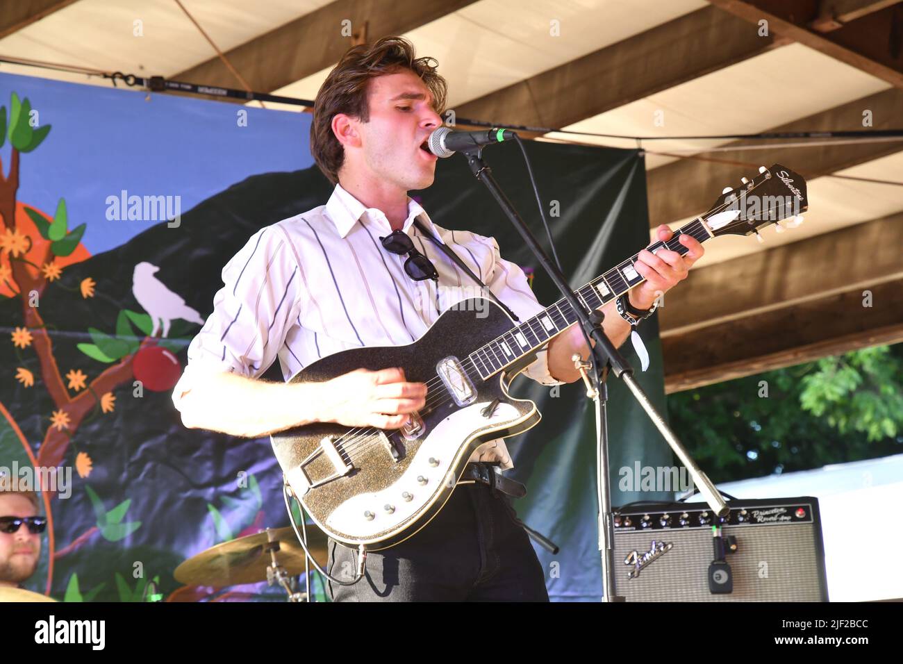 Musician Jake Manzi shown performing on stage during a “live” concert ...