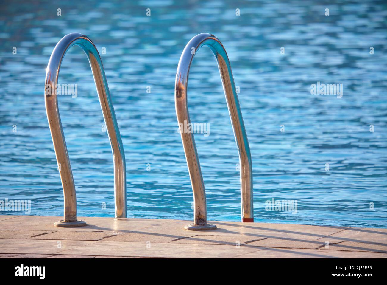 Close up of swimming pool stainless steel handrail descending into ...