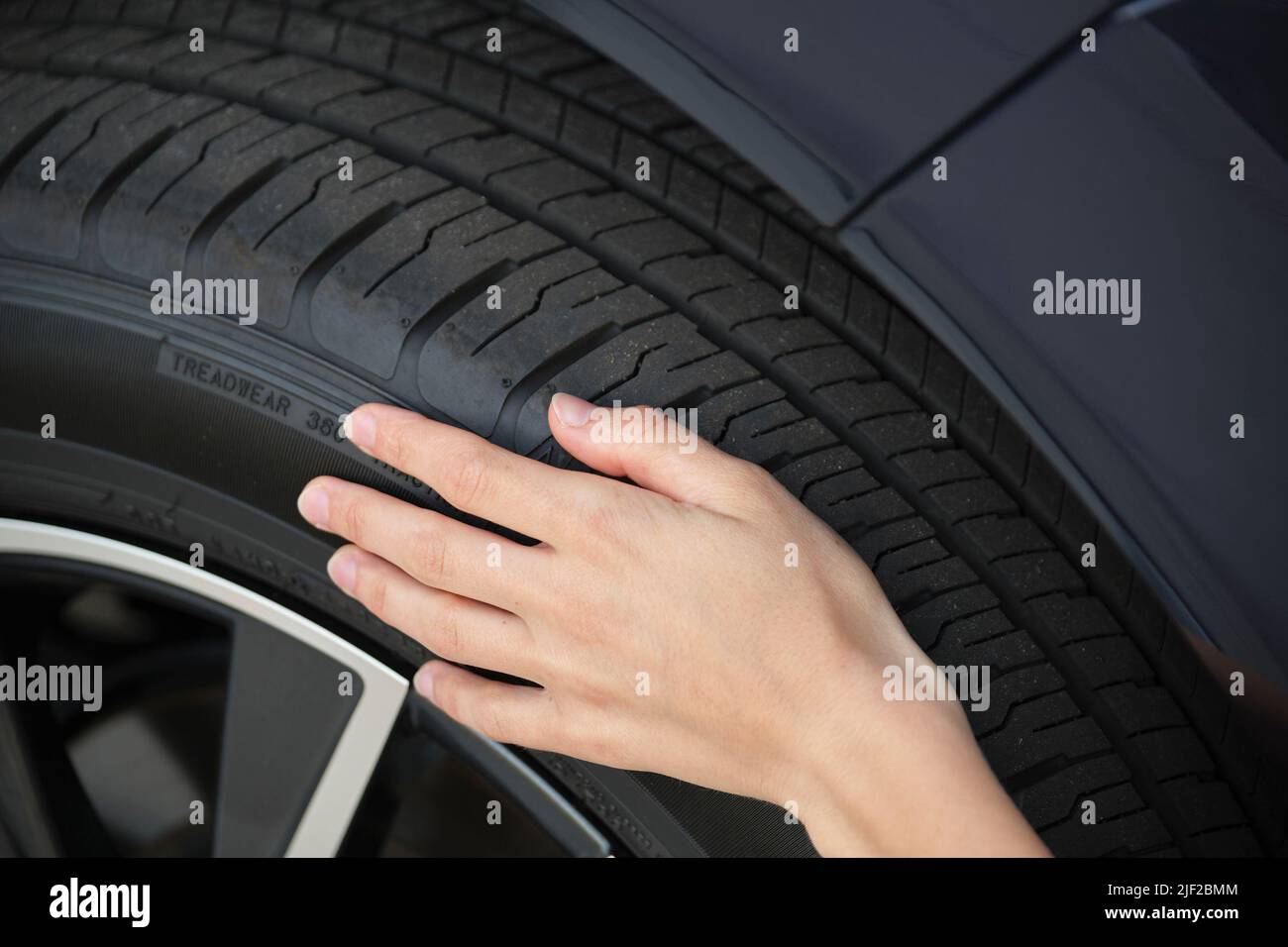 Female driver hands inspecting wheel tire of her new car. Vehicle ...