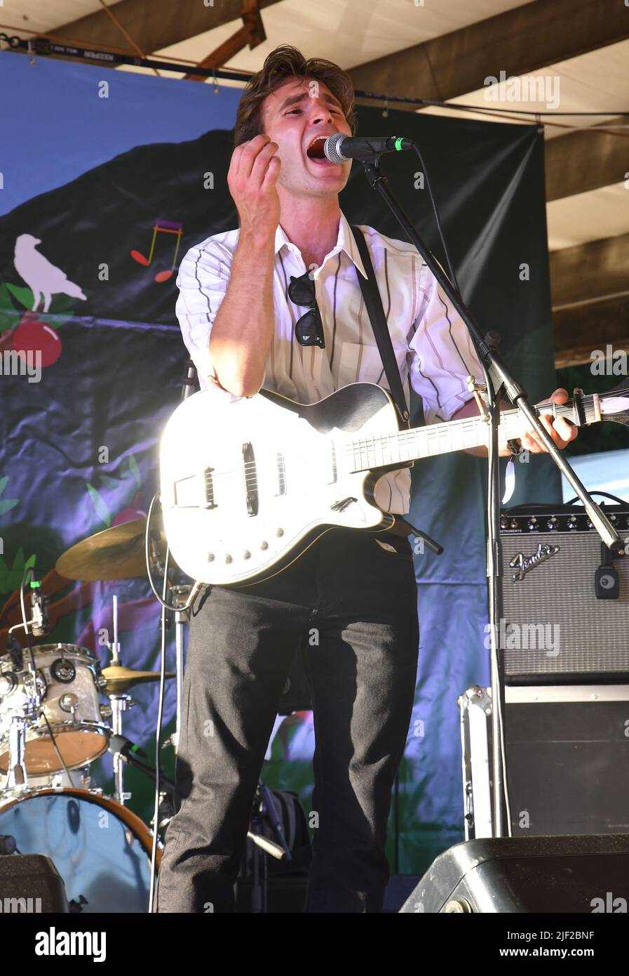 Musician Jake Manzi shown performing on stage during a “live” concert ...