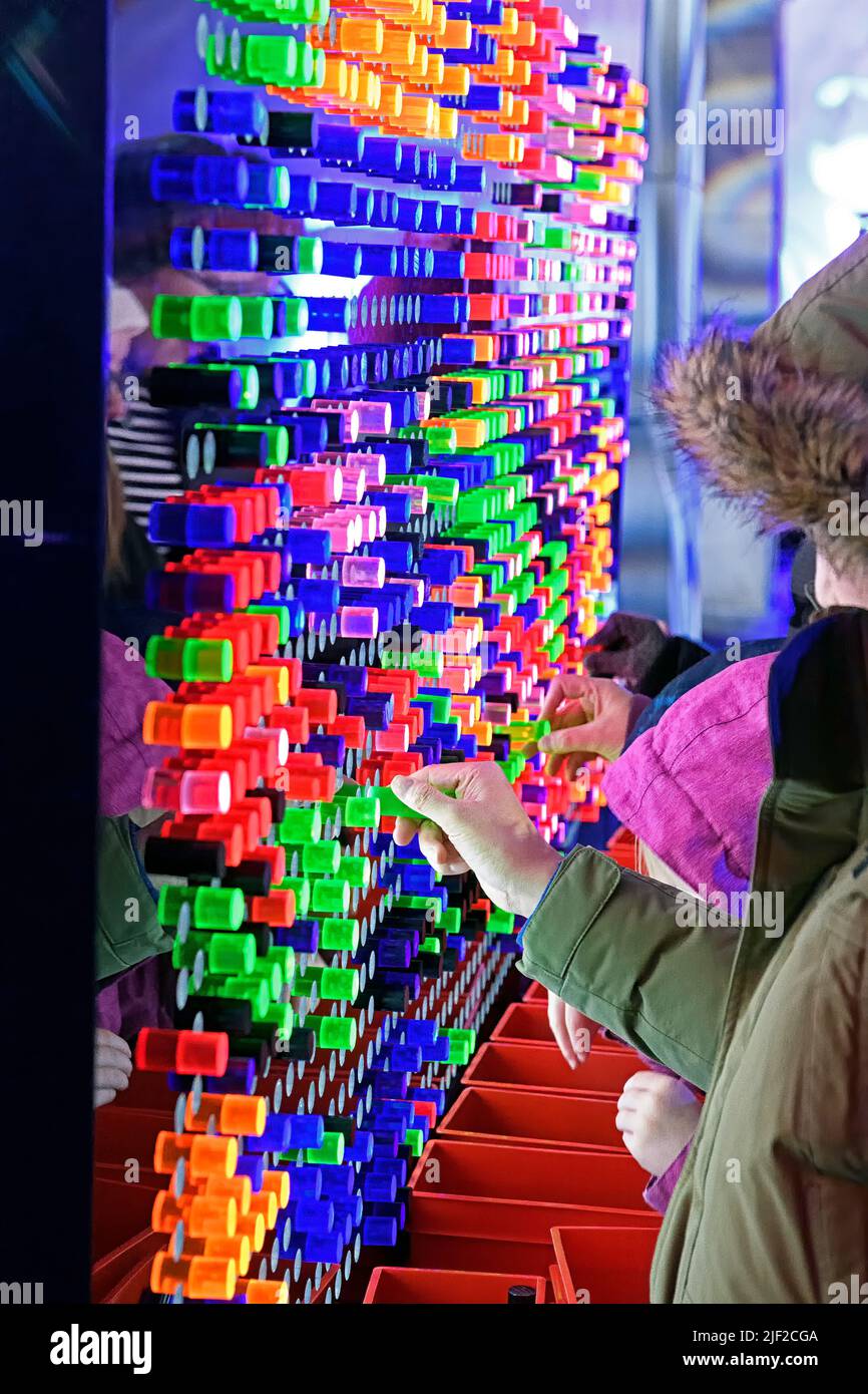 Children playing with an illuminated light peg mural using colored ...