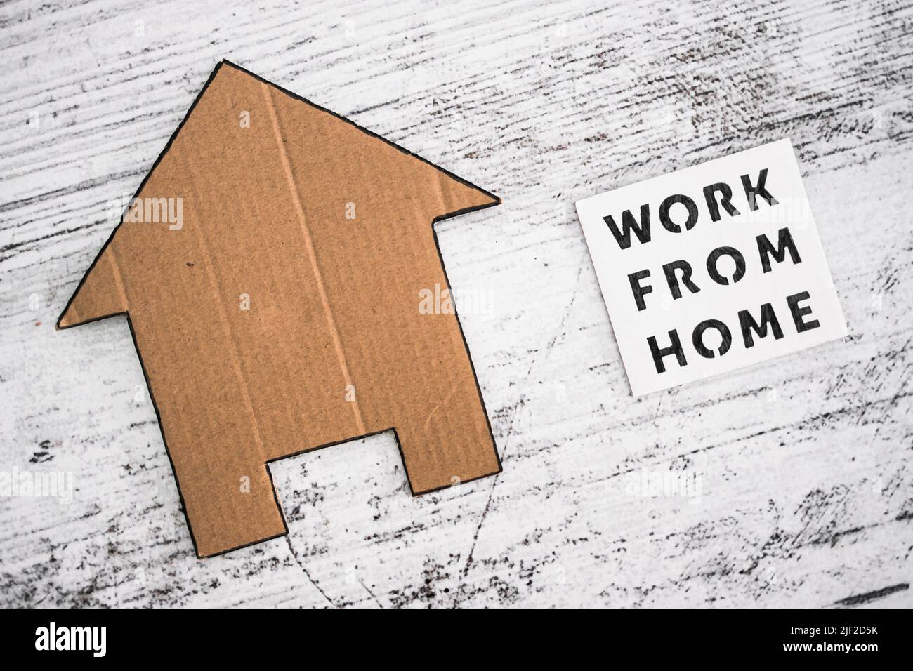 work from home sign with house icon made of cardboard over white wooden ...