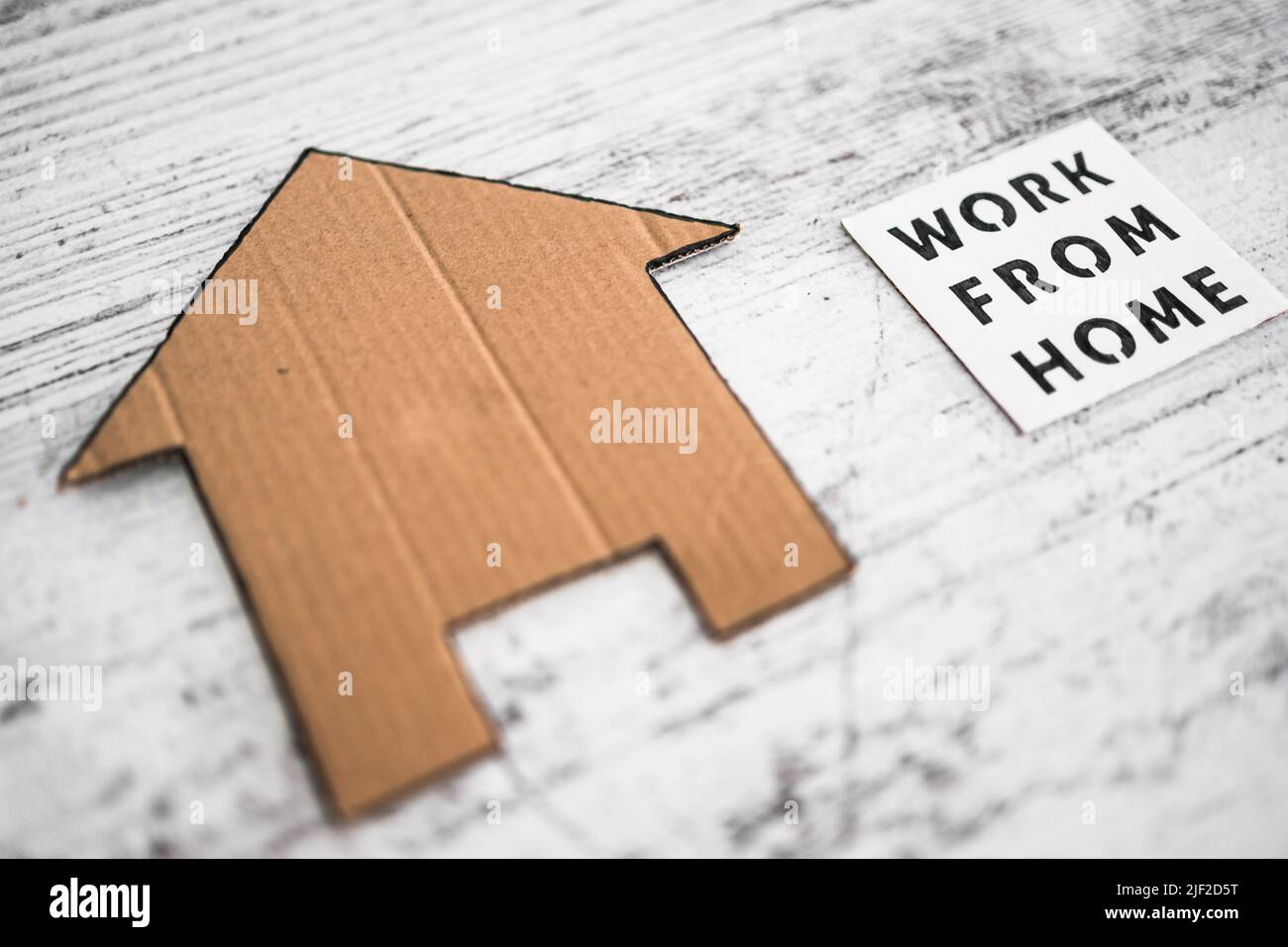 work from home sign with house icon made of cardboard over white wooden ...