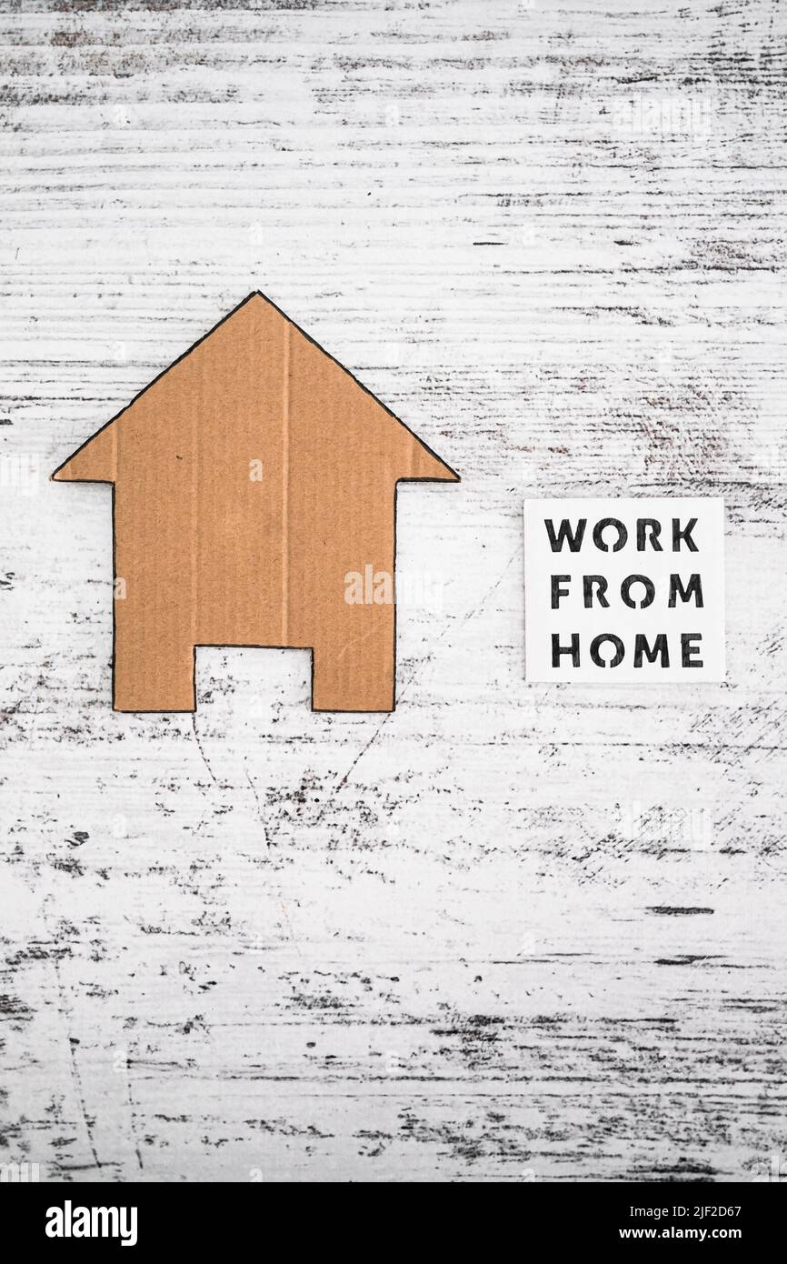 work from home sign with house icon made of cardboard over white wooden ...