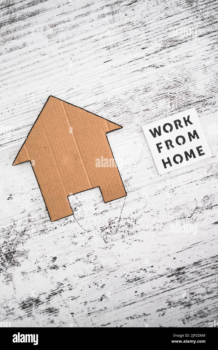 work from home sign with house icon made of cardboard over white wooden ...