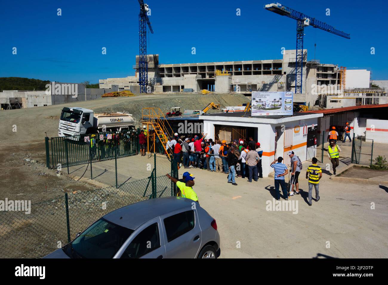 workers waiting for work at a building site with cranes and cement work ...