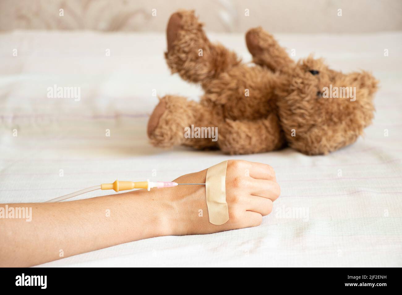 Children's hand with a dropper on the bed and next to it lies a ...