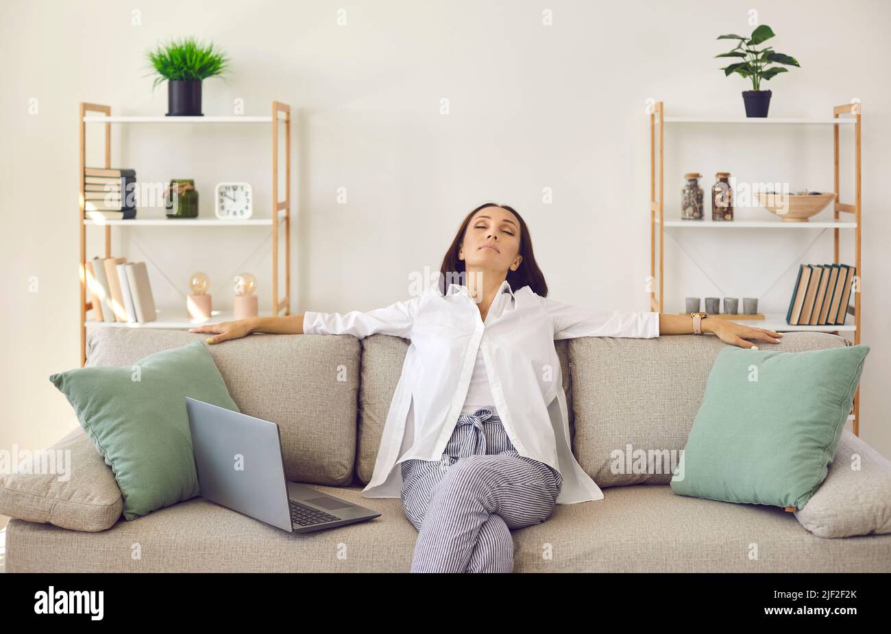 Happy woman relaxing on a comfortable couch in the living room of her ...
