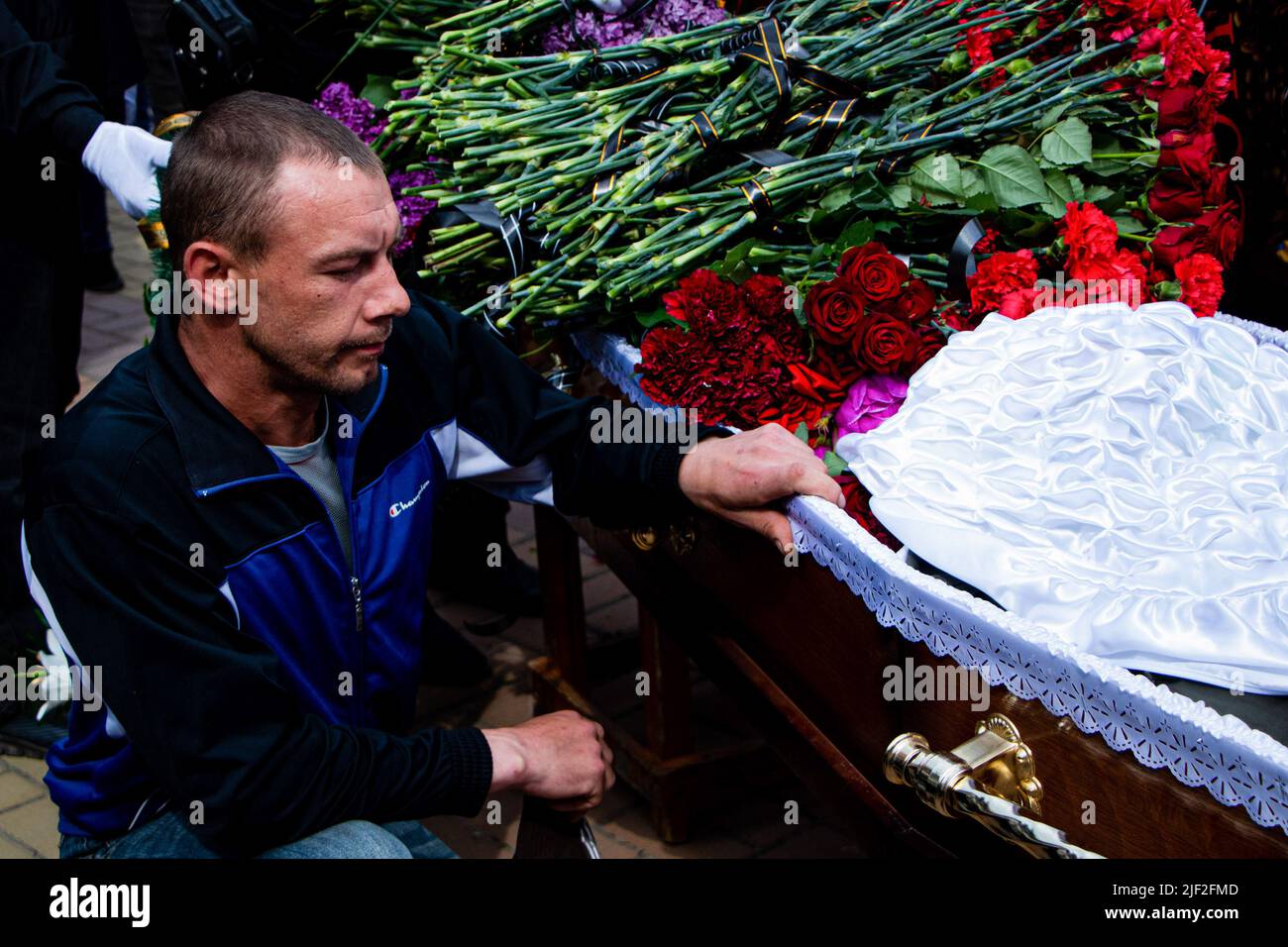 Friend is standing on the coffin of Sergey Titov. Family, relatives, and friends are attending ...