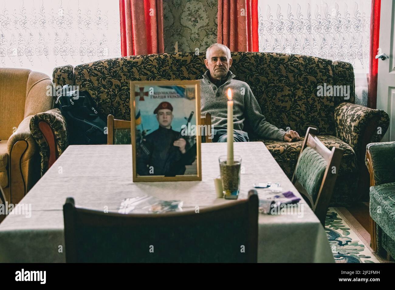 Father of Sergey Titov is sitting in his living room. Family, relatives, and friends are ...