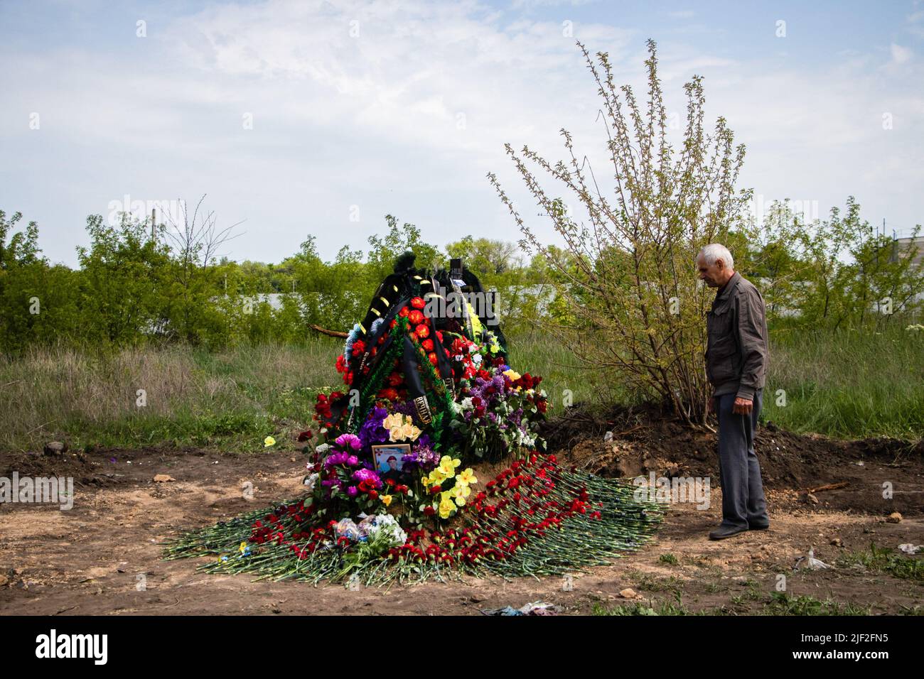 Father of Sergey Titov is standing at the grave of his son. Family, relatives, and friends are ...