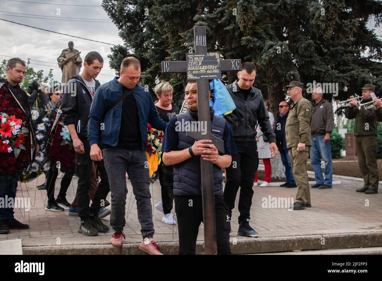 Mourners are walking behind the cross to the cemetery to bury Sergey Titov. Family, relatives ...