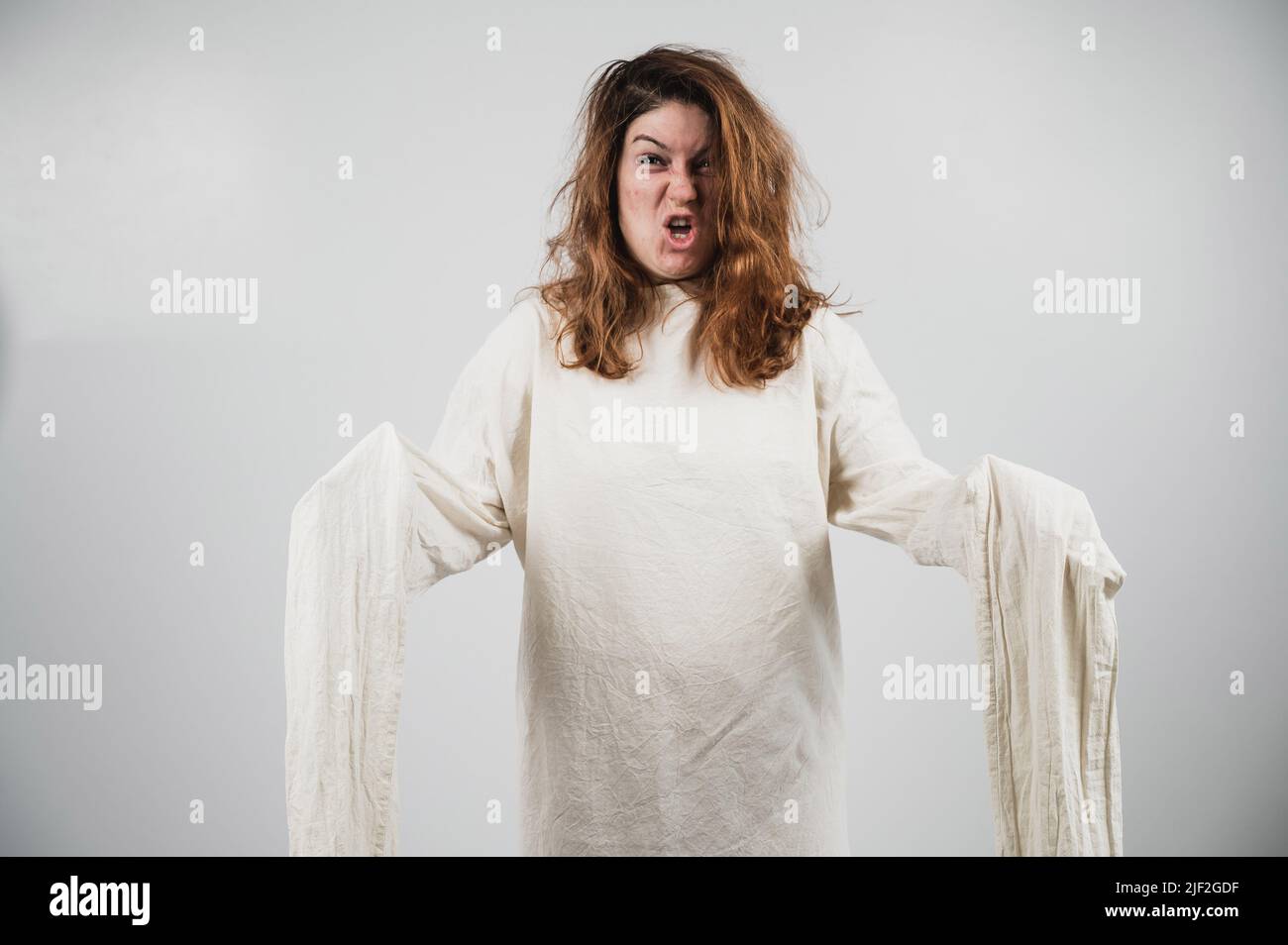 Close-up portrait of insane woman in straitjacket on white background ...