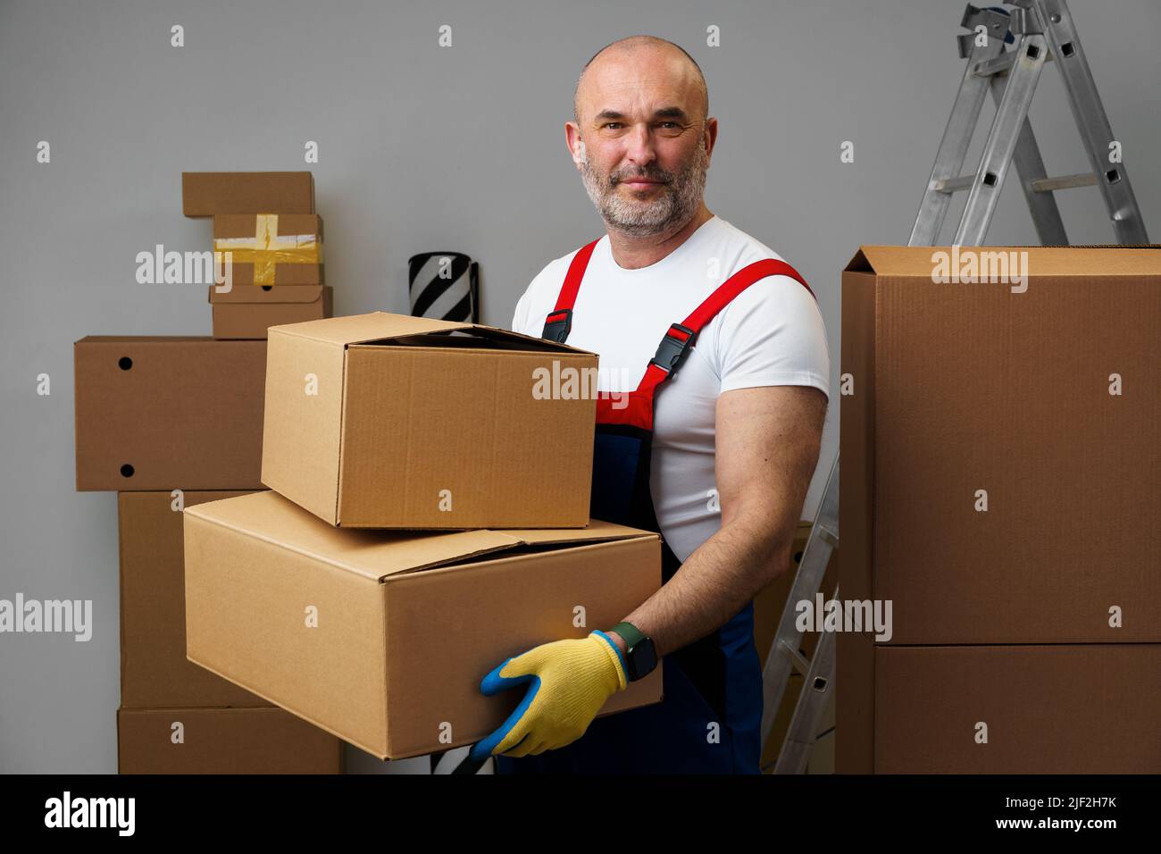 Middle-aged man mover in uniform holding cardboard box, portrait Stock ...