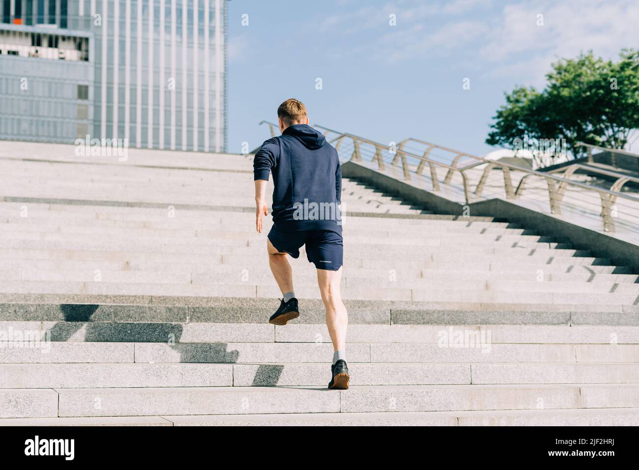 Young athlete man runner running up and down on city stairs in summer ...