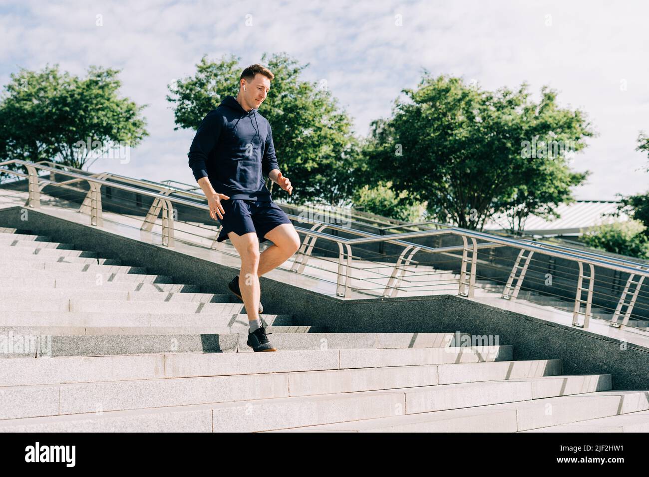Young athlete man runner running up and down on city stairs in summer ...