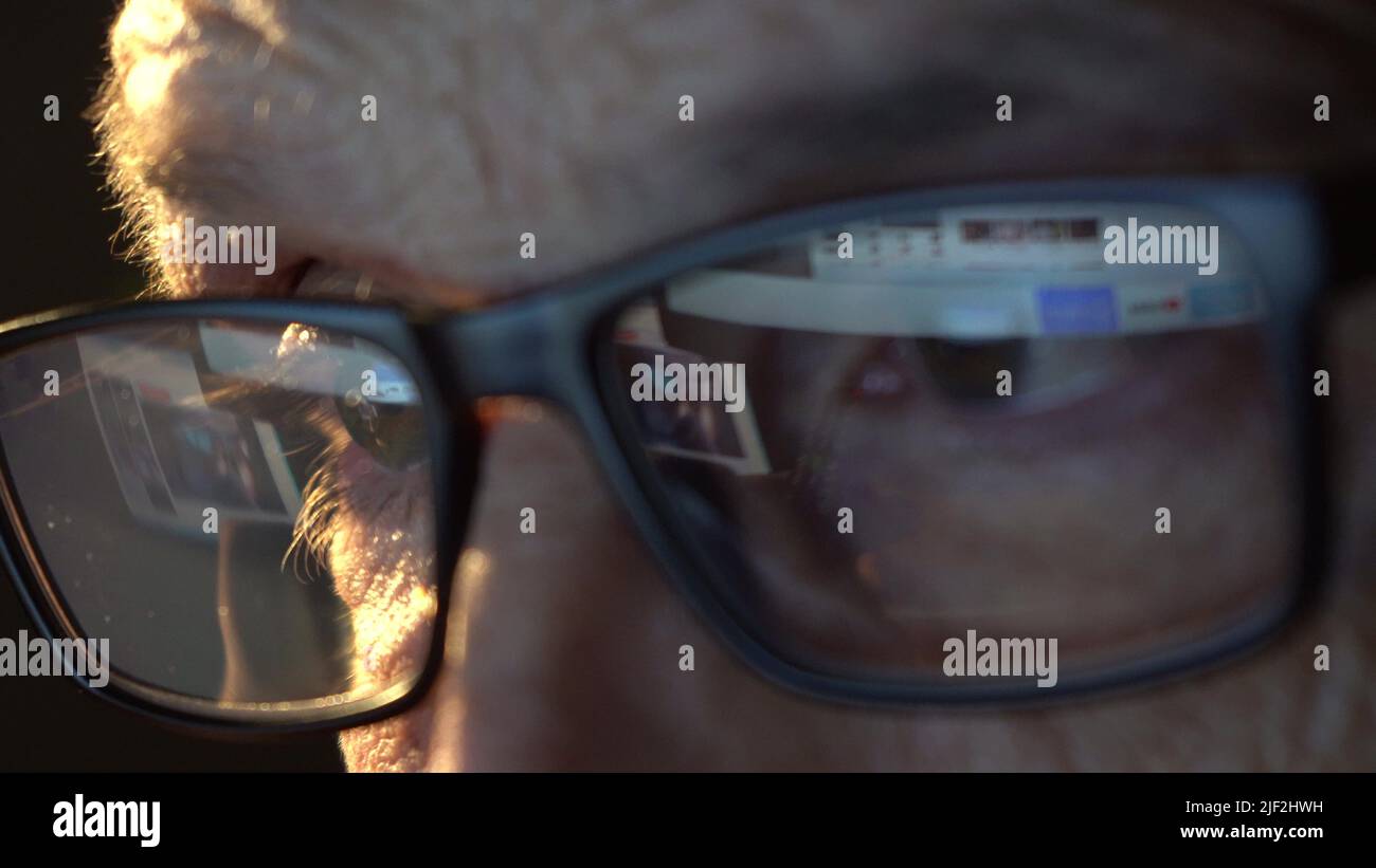 Close-up of the focused eyes of a businessman wearing computer glasses ...