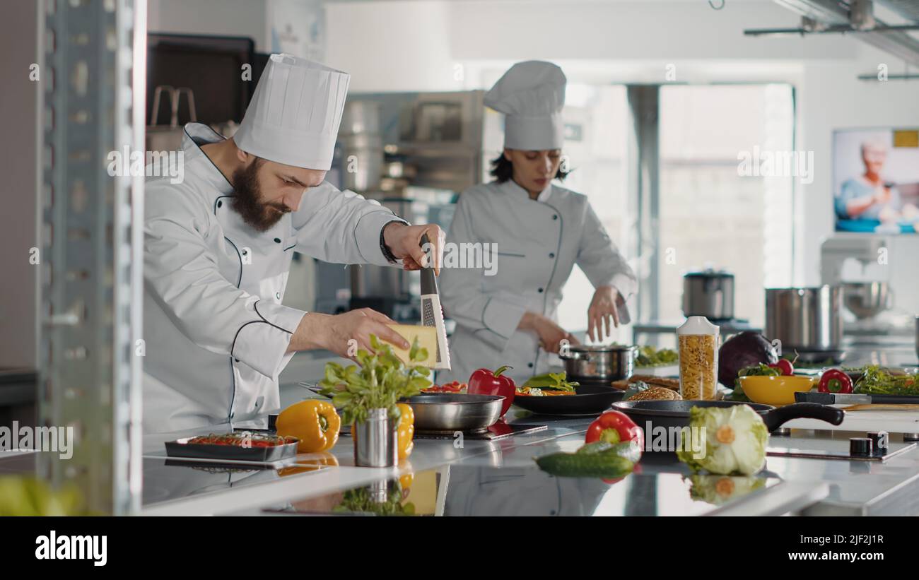 Authentic cook grating parmesan cheese on gourmet dish, preparing ...