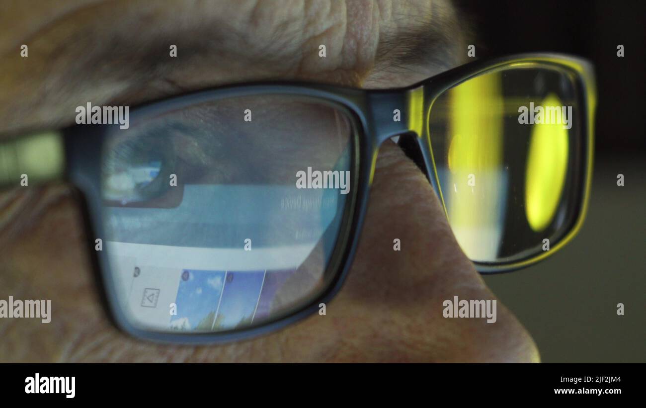 An elderly man with glasses looks at the computer screen Stock Photo ...