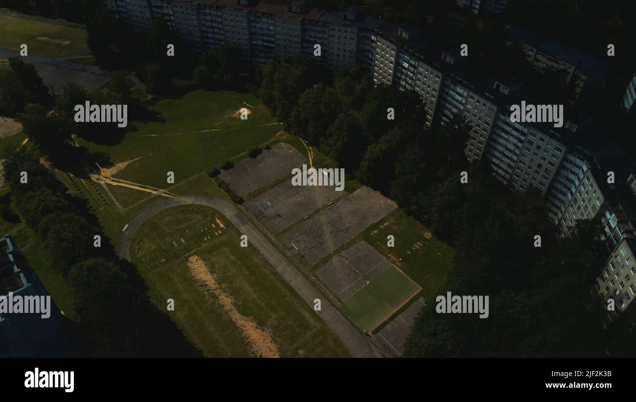 An old school stadium in a city block. Cracked asphalt and sports ...