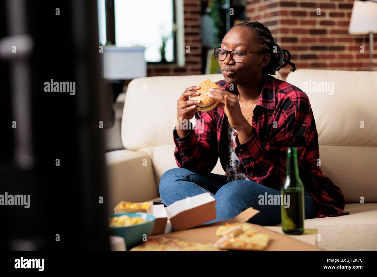 Happy female adult eating burger from fast food delivery takeout ...