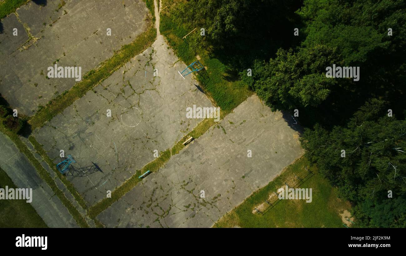 An old school stadium in a city block. Cracked asphalt and sports ...