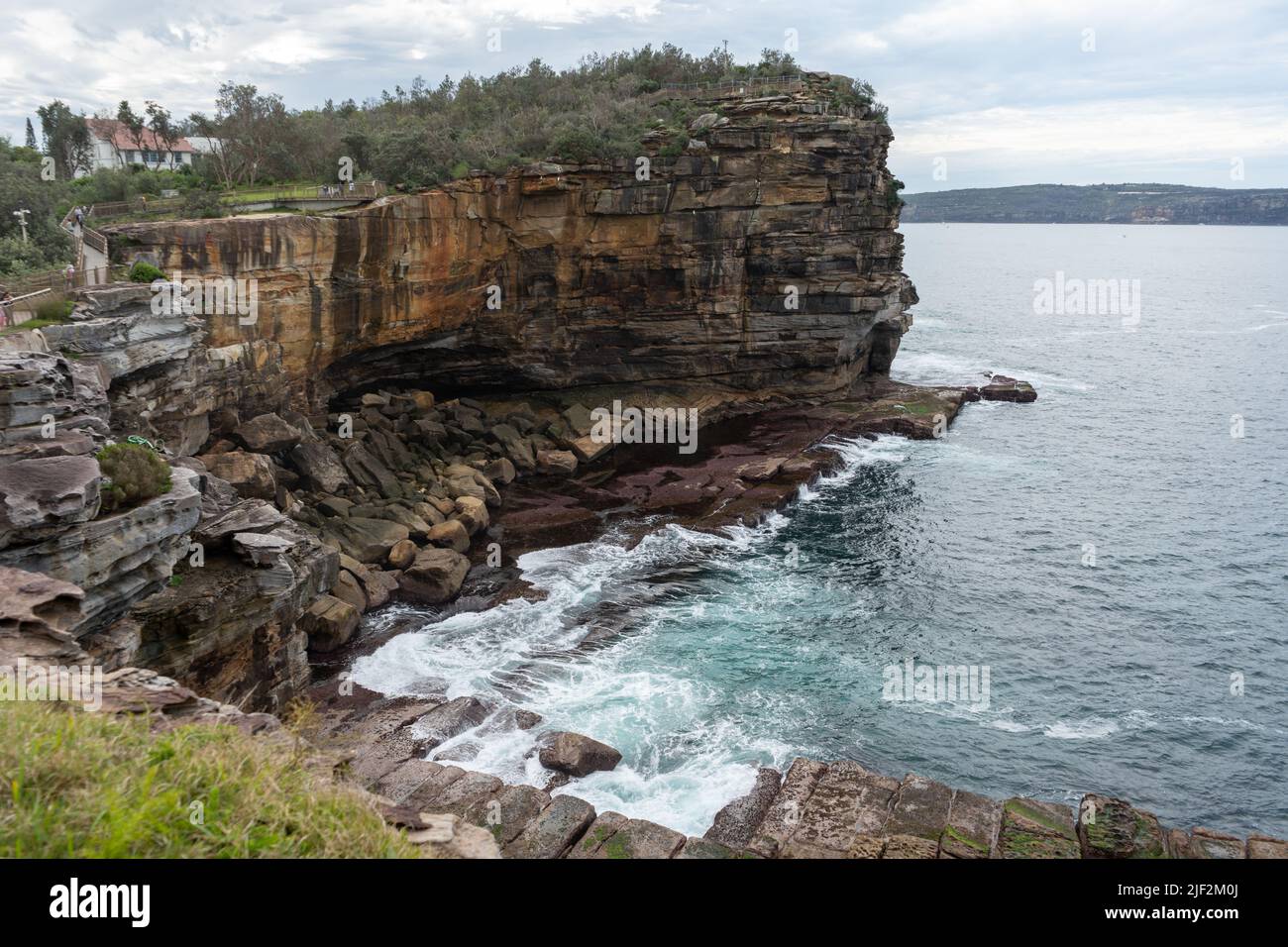 A scenic view of a rocky cliff covered with greenery against a blue sea ...