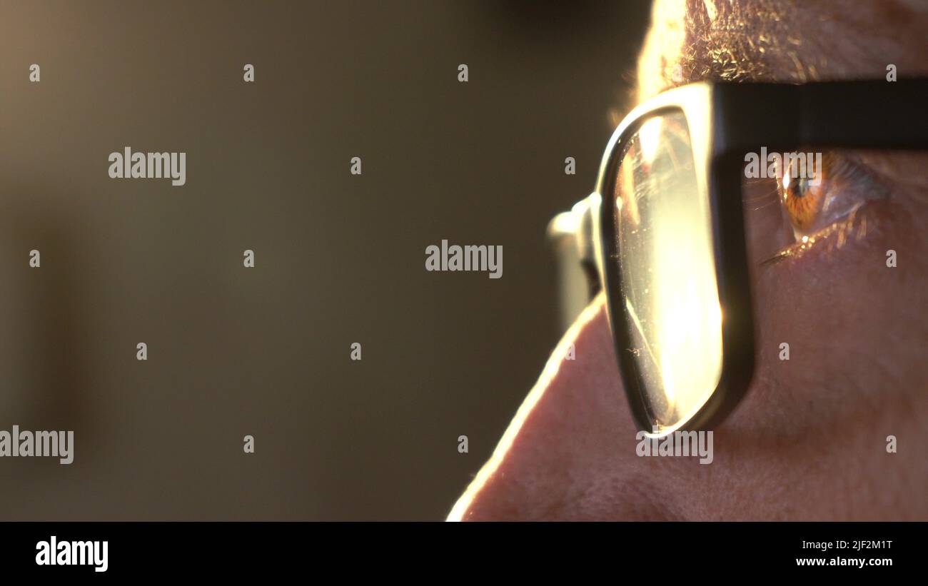 Close-up of the focused eyes of a businessman wearing computer glasses ...