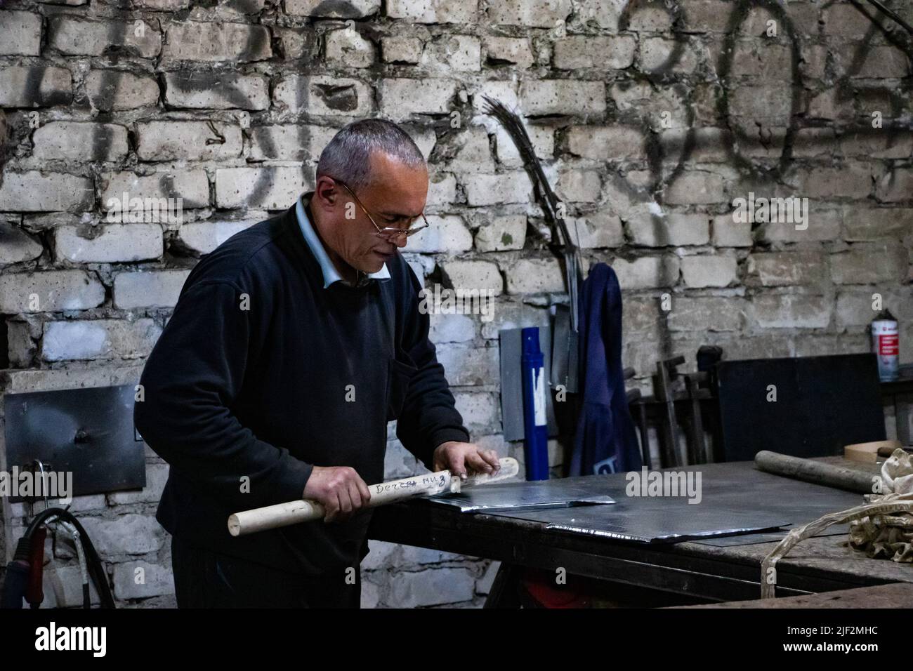 Ukrainian worker roles rolling pin over the metal plate to get rid off ...