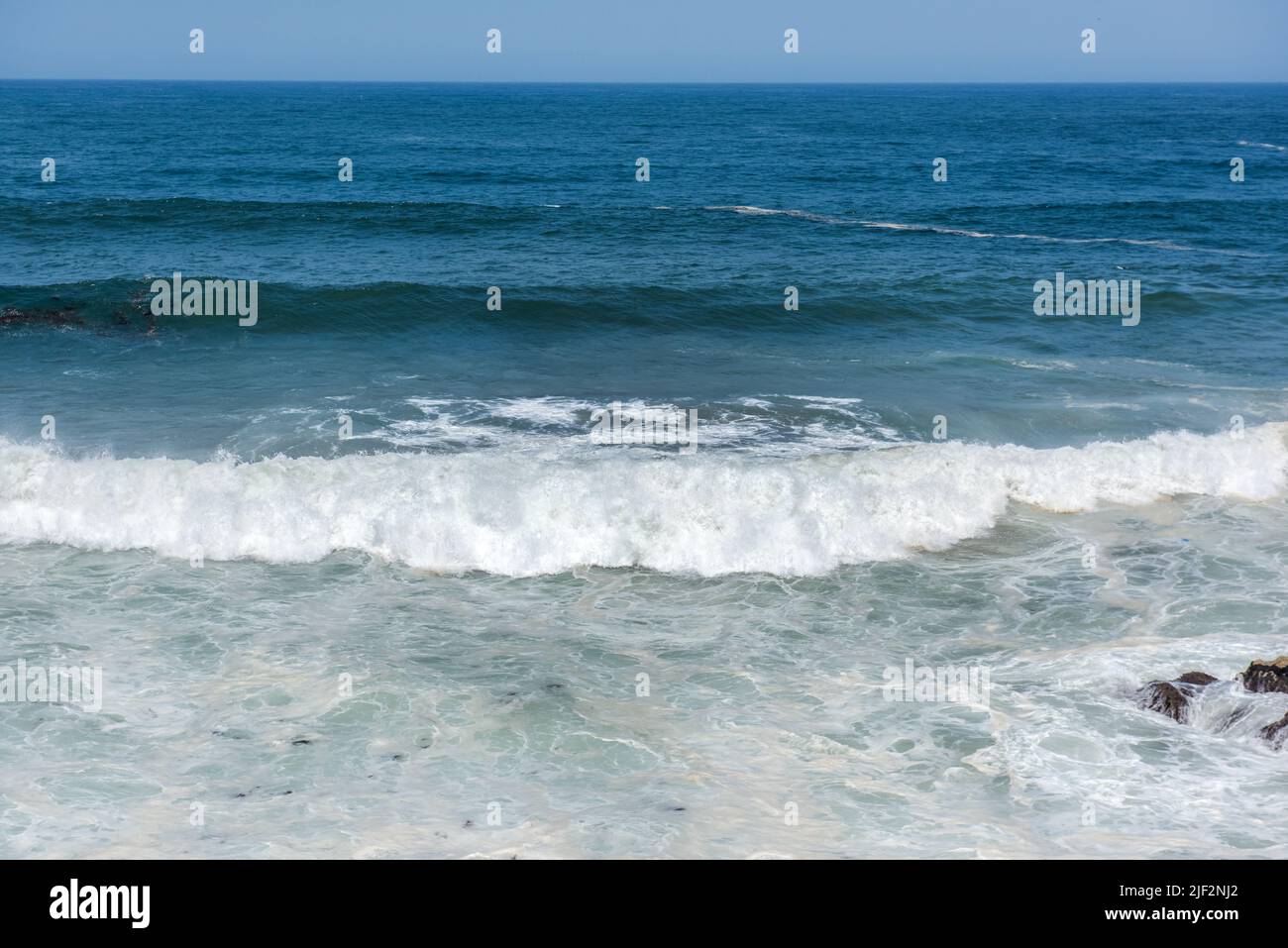 The huge waves crashing into ston island against the blue sky and ...