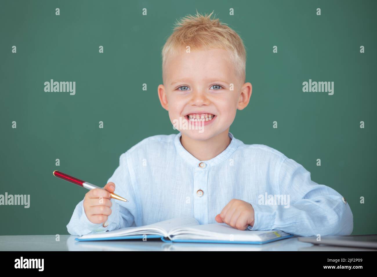 Kid writing in notebook in class. Little student child studying in ...
