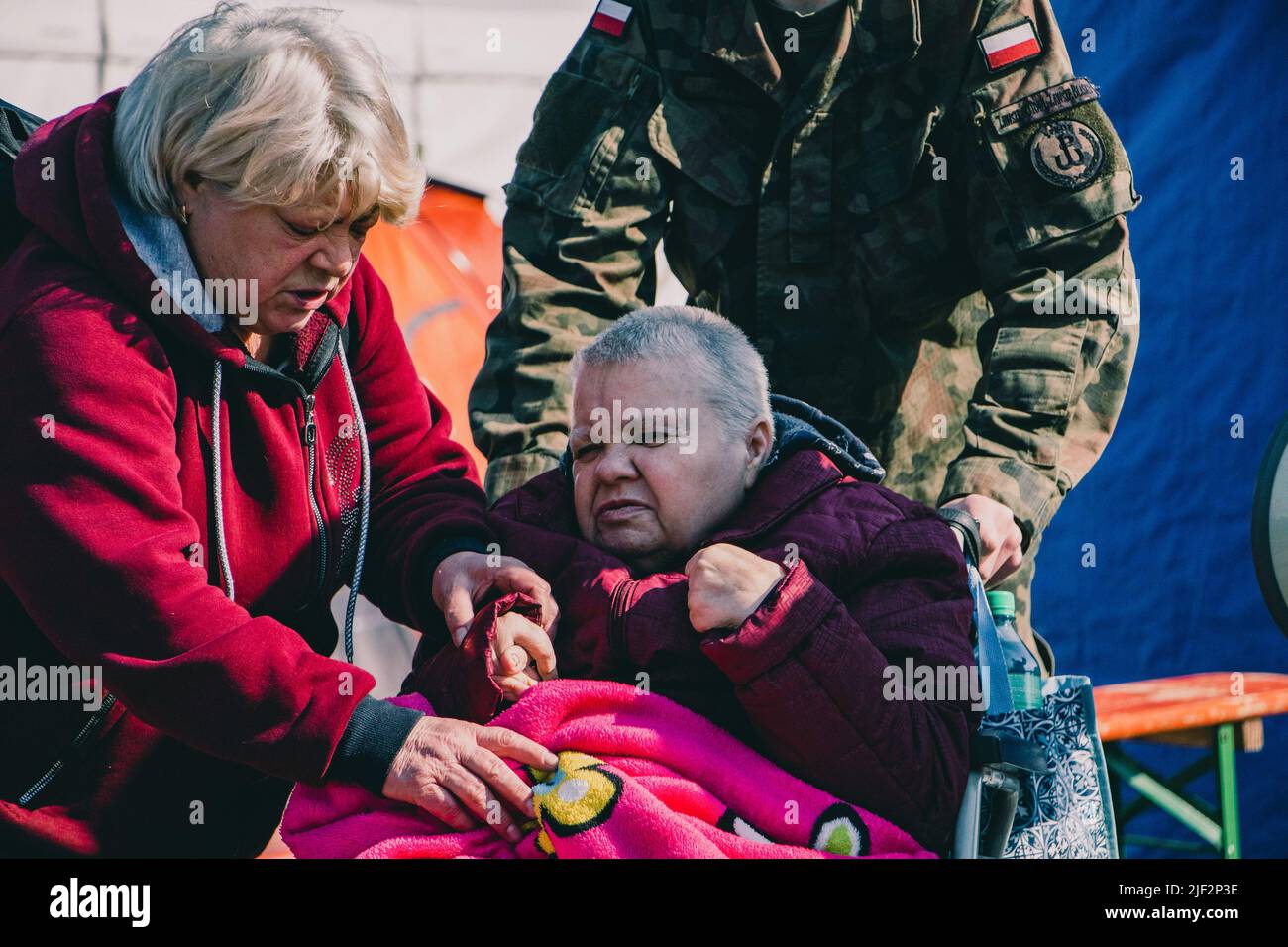 Medyka, Poland. 15th Mar, 2022. Woman in a wheelchair gets help from a ...