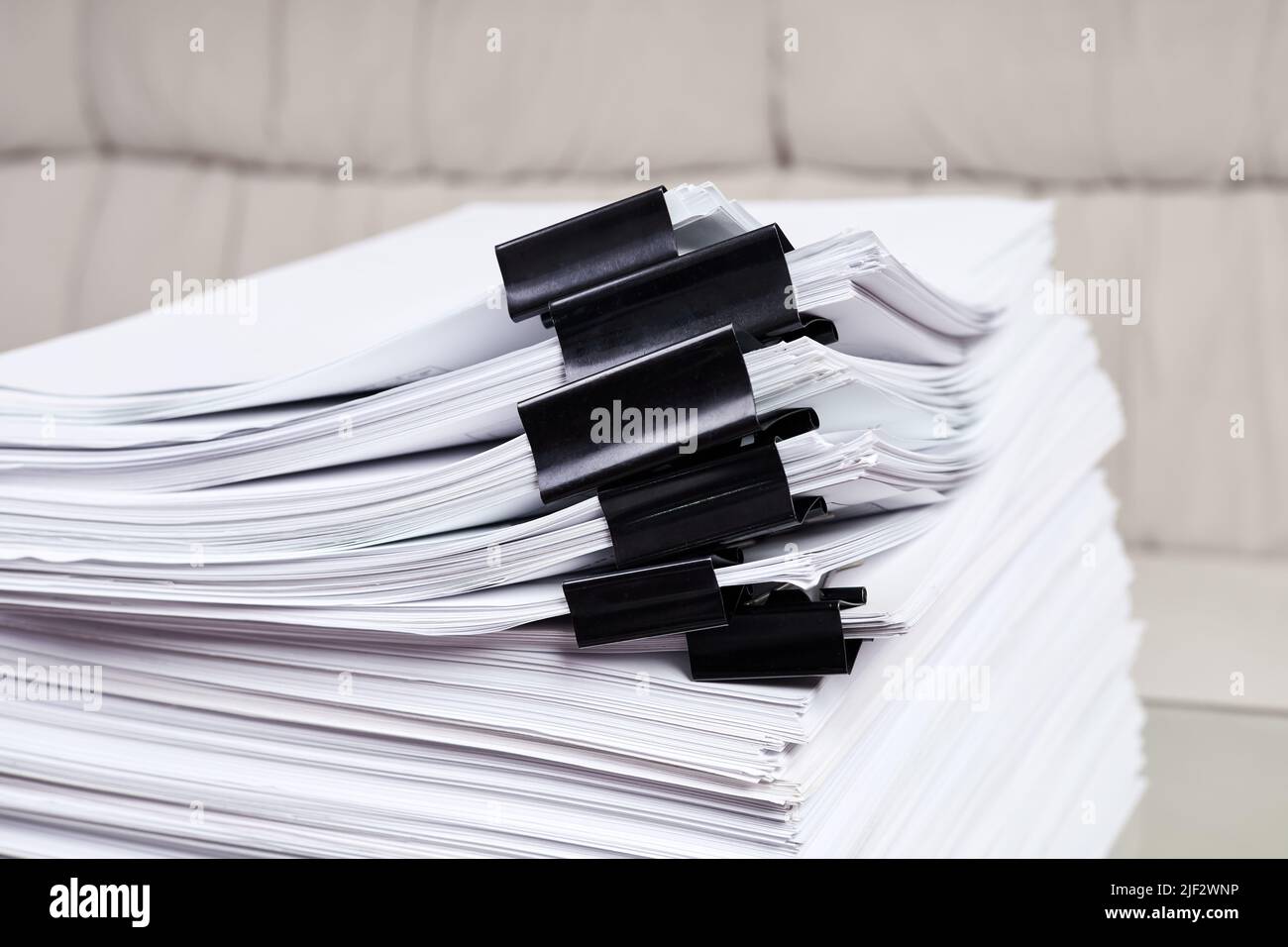A stack of office papers, some of which are fastened with black binders ...