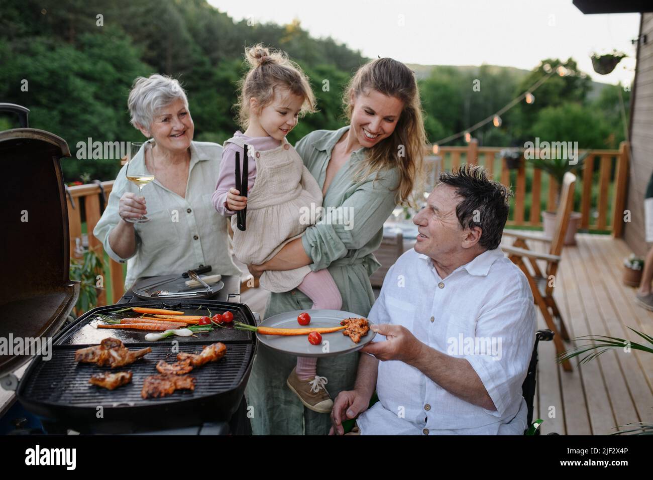 Multi generation family grilling outside on patio in summer during ...