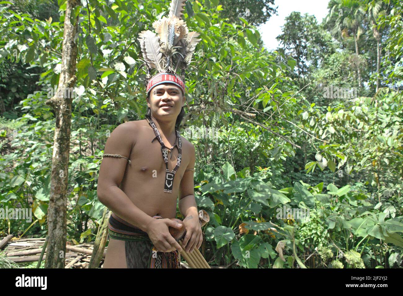 A tourism worker wearing indigenous attire is posing for tourists at ...