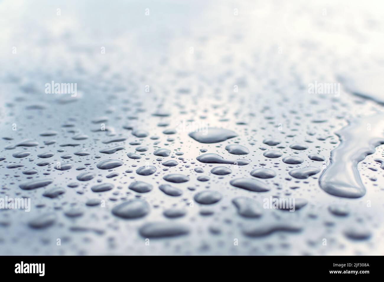 Drops of pure water on a smooth mirror reflective surface after rain or ...