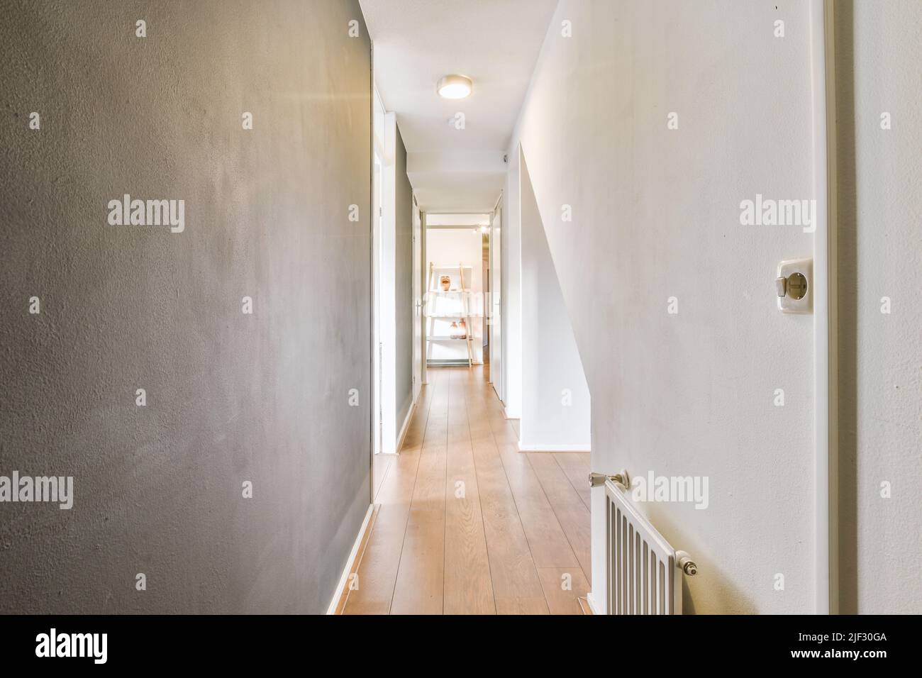 Perspective view of empty narrow hallway with white walls and wardrobe ...
