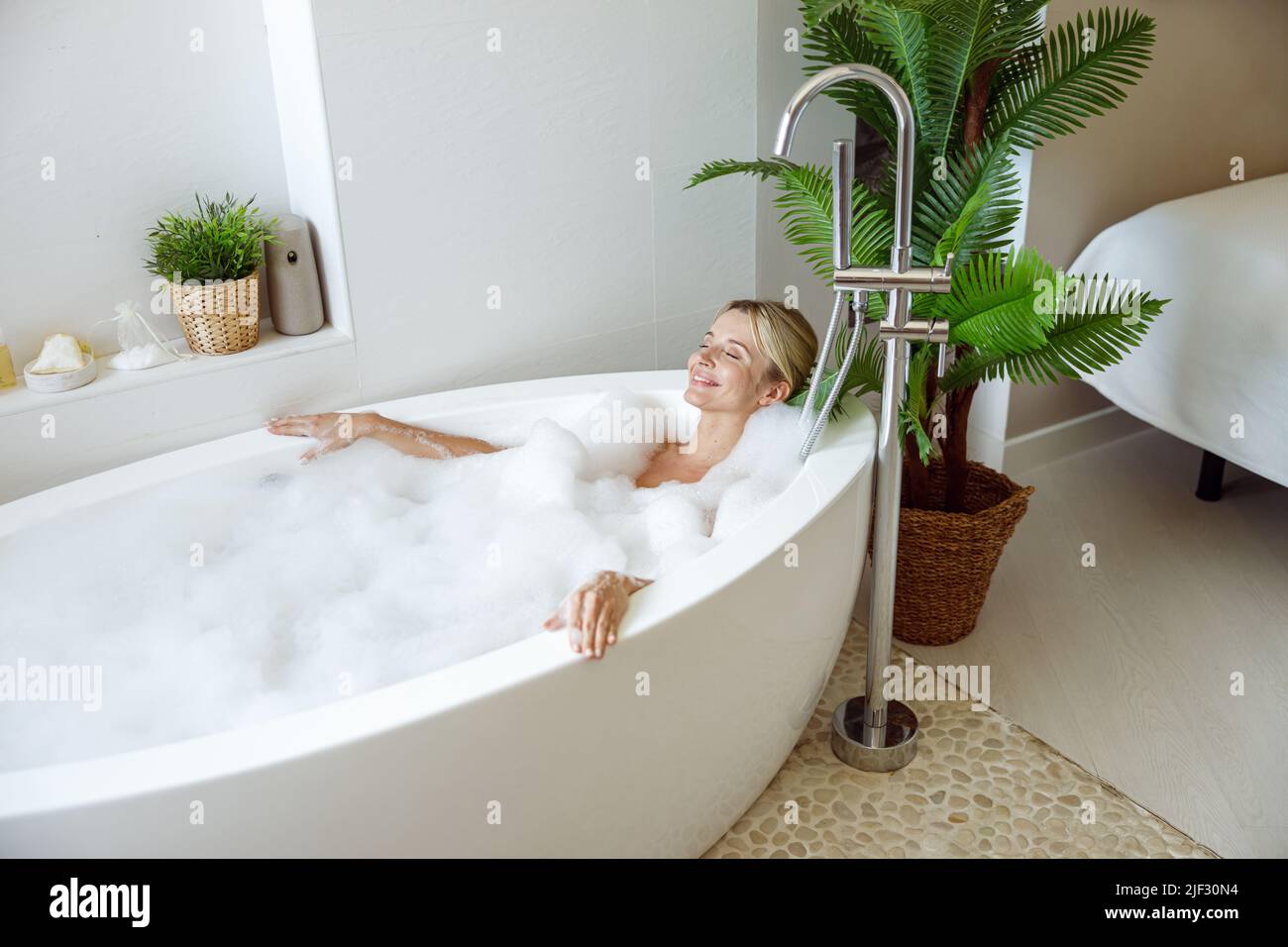 View from above on young beautiful female lying in warm bath, smiling ...