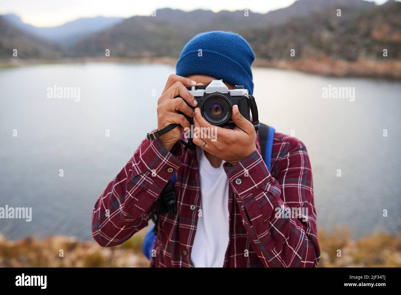 An hiking man takes a photo using vintage camera, lake view mountains ...