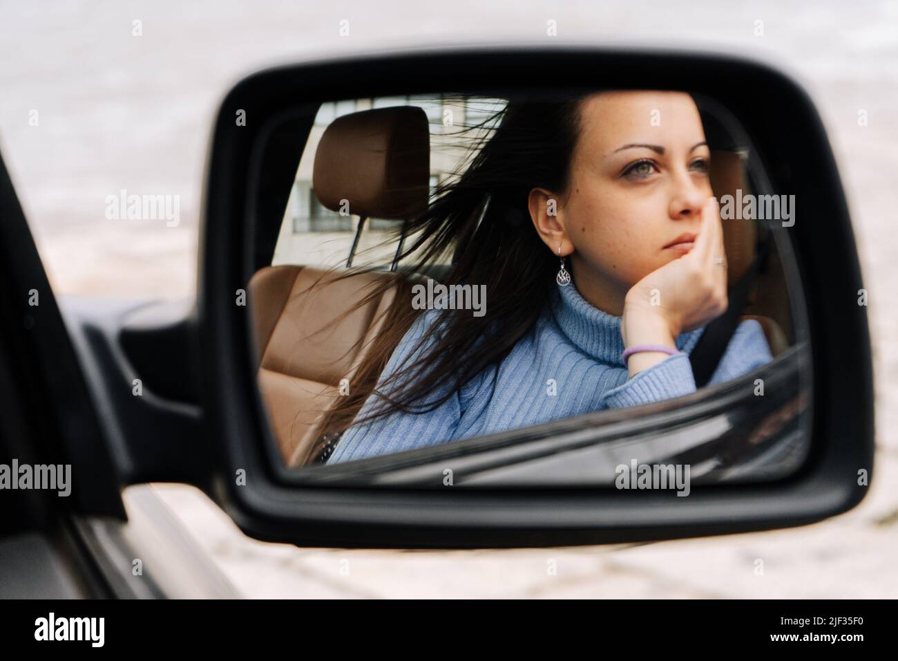 Mirror portrait of a young woman sitting on the passenger seat of a car ...
