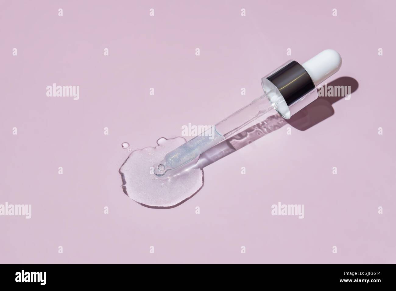 Transparent pipette with blue cosmetics serum on a light pink ...