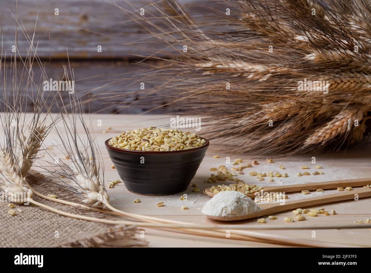 Bowl full of tender wheat seeds and dried ears of wheat along with a ...