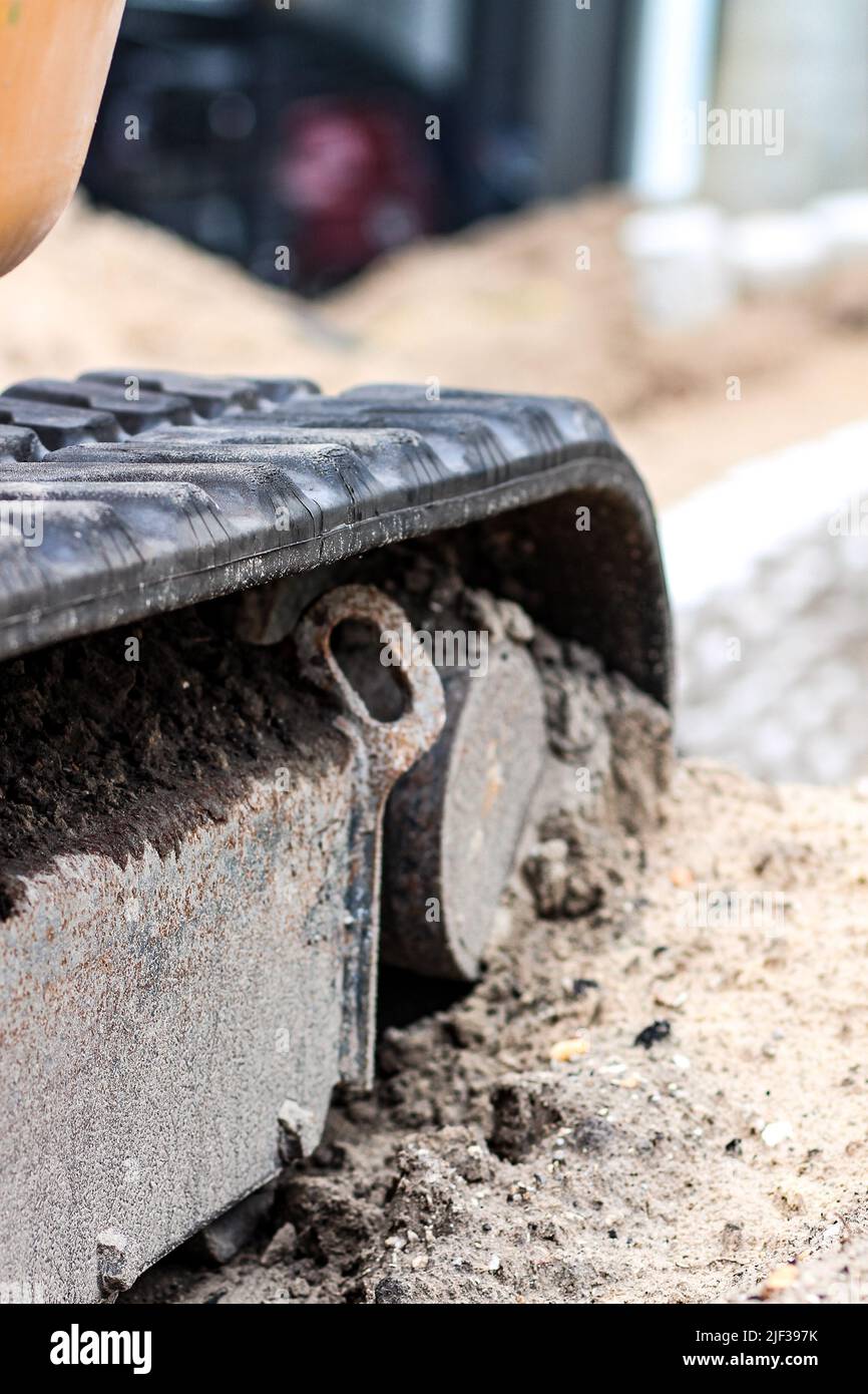 A vertical shot of an excavator track rubber tires during construction ...